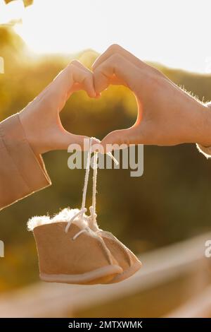Man and pregnant wife are doing heart gesture with hands and holding ...