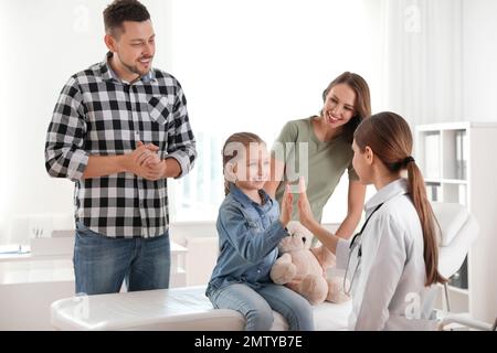 Pediatrician visiting parents and child in hospital bed ward, doctor ...