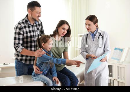 Pediatrician visiting parents and child in hospital bed ward, doctor ...