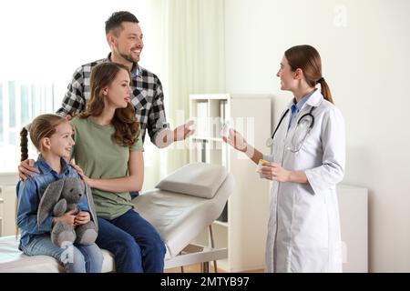 Pediatrician visiting parents and child in hospital bed ward, doctor ...