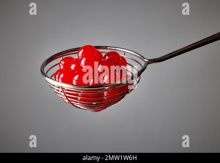 red jelly balls for making bubble tea in a strainer on grey background ...