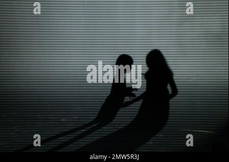 kid's shadows on wall. shadow of two children, boy and girl on striped ...