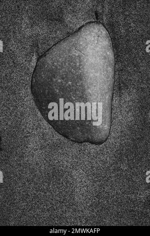 A vertical greyscale shot a rock at the beach Stock Photo - Alamy