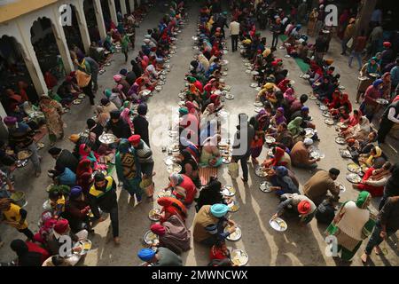 Sikh devotees eat a meal from a community kitchen at a gurudwara, or ...