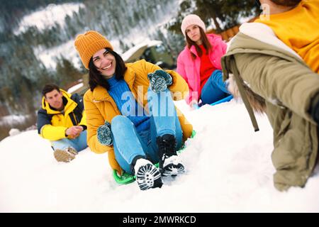 Group of friends having fun and sledding on snow. Winter vacation Stock ...