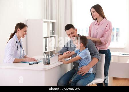 Pediatrician visiting parents and child in hospital bed ward, doctor ...
