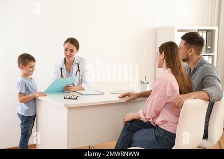 Pediatrician visiting parents and child in hospital bed ward, doctor ...