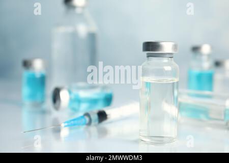 Vials and syringe on light table, space for text. Vaccination and ...