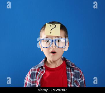 Emotional little boy with question mark on blue background Stock Photo ...