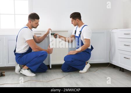 Maintenance workers installing new kitchen furniture indoors Stock ...