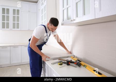 Worker installing new countertop in modern kitchen Stock Photo - Alamy
