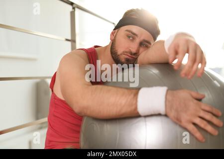 Lazy young man with exercise ball indoors Stock Photo - Alamy
