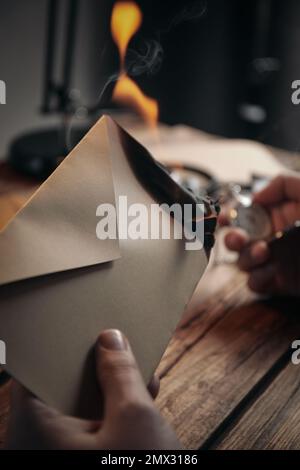 Detective with burning envelope and pocket watch at wooden table ...