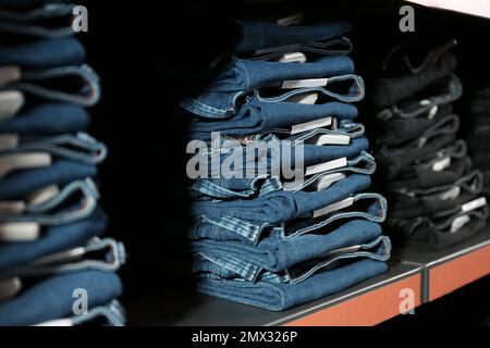 Collection of stylish jeans on shelf in shop Stock Photo - Alamy