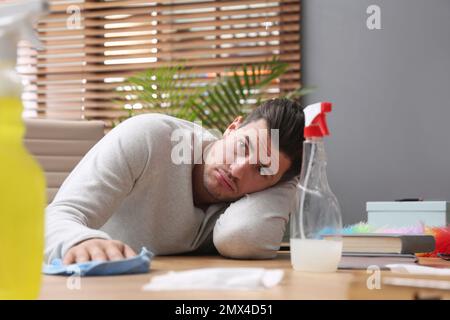 Lazy man procrastinating while cleaning at home Stock Photo - Alamy