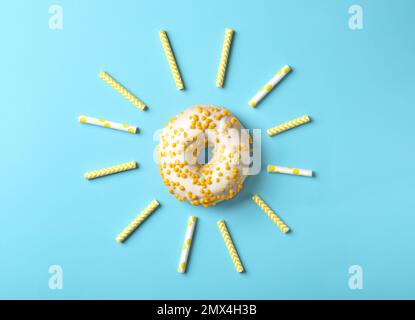 Sun made with donut and straws on light blue background, flat lay ...