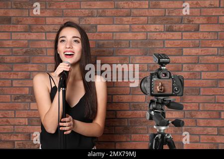 Music teacher recording singing lesson near brick wall Stock Photo - Alamy