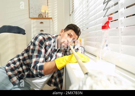 Lazy man procrastinating while cleaning at home Stock Photo - Alamy