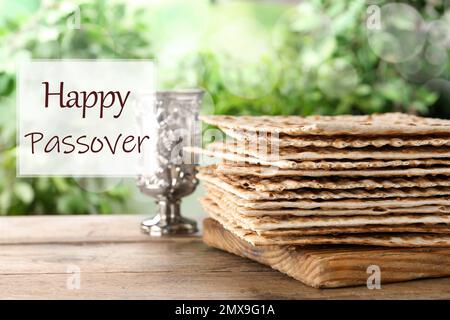 Traditional Matzos and silver goblet on wooden table, space for text ...