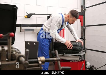 Mechanic working with tire fitting machine at car service Stock Photo ...