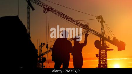 Silhouettes of engineers near construction site at sunset. Banner ...