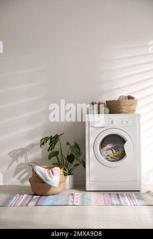 Modern washing machine with laundry near color wall Stock Photo - Alamy