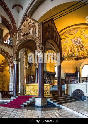The apse of an old romanesque church with golden reredos and a mural ...