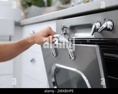 Man using modern oven in kitchen, closeup Stock Photo - Alamy