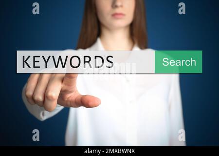 Woman pointing at search bar with text KEYWORDS on light grey ...