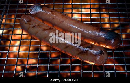 Two hot dogs cooking over a small campfire Stock Photo - Alamy