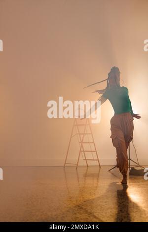 Vertical image of biracial female modern dancer dancing in smoked ...