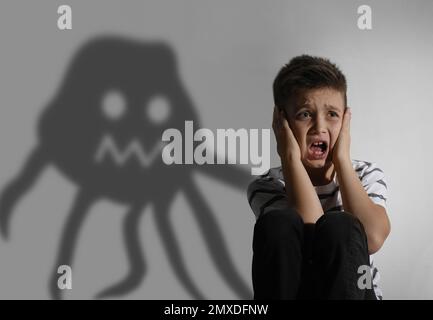 Scared little boy suffering from sciophobia and phantom behind him ...
