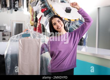 Happy client with clothes near counter at dry-cleaner's Stock Photo - Alamy