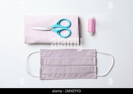 Homemade protective mask, threads and scissors on white background ...