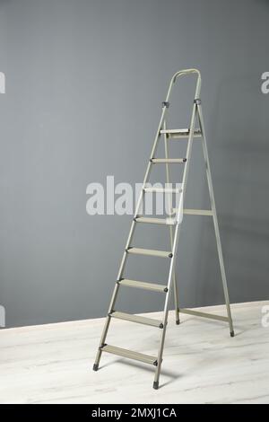Modern metal stepladder near grey wall indoors. Space for text Stock ...