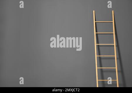Modern wooden ladder on grey background. Space for text Stock Photo - Alamy