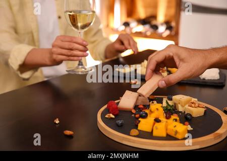 Couple with different types of delicious cheeses at table indoors ...