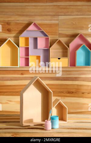 House shaped shelves with jars of paints and brushes on wooden wall ...
