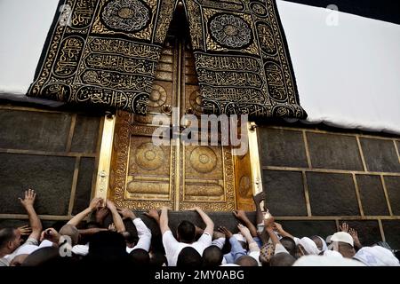 Muslim pilgrims touch the golden door of the Kaaba, the cubic building ...