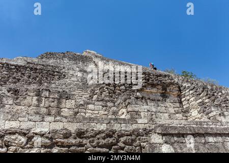 Visitors climbing the steps of structure IX of the Mayan ruins at Becán ...