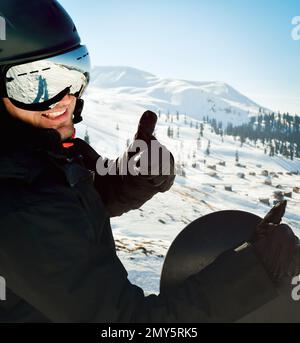 Happy male skier showing thumbs up on a mountain ski resort Stock Photo ...