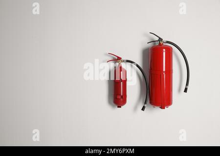 Different fire extinguishers hanging on white wall Stock Photo - Alamy