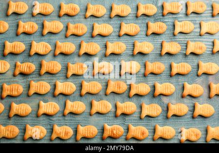 Delicious goldfish crackers on blue background, flat lay. Space for ...
