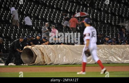 Grounds crew members unroll the tarp during a sudden rainstorm in the ...