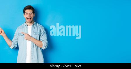 Excited handsome 25s years man with beard, pointing fingers left and ...