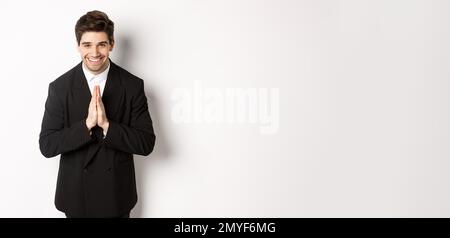 Handsome guy saying thank you, bowing and holding hands in namaste ...