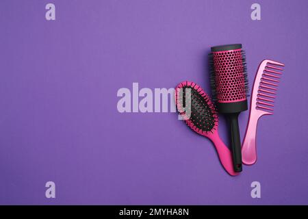 Comb brushes on purple background Stock Photo - Alamy