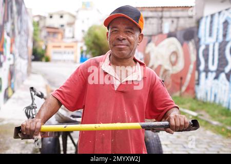 Keeping it clean. Portrait of a garbage collector with his cart in the ...