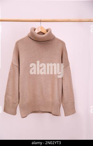 Rack with knitted clothes near light wall, closeup Stock Photo - Alamy