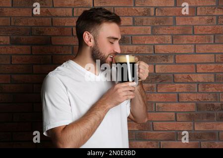 Handsome man with cold kvass near brick wall. Traditional Russian ...